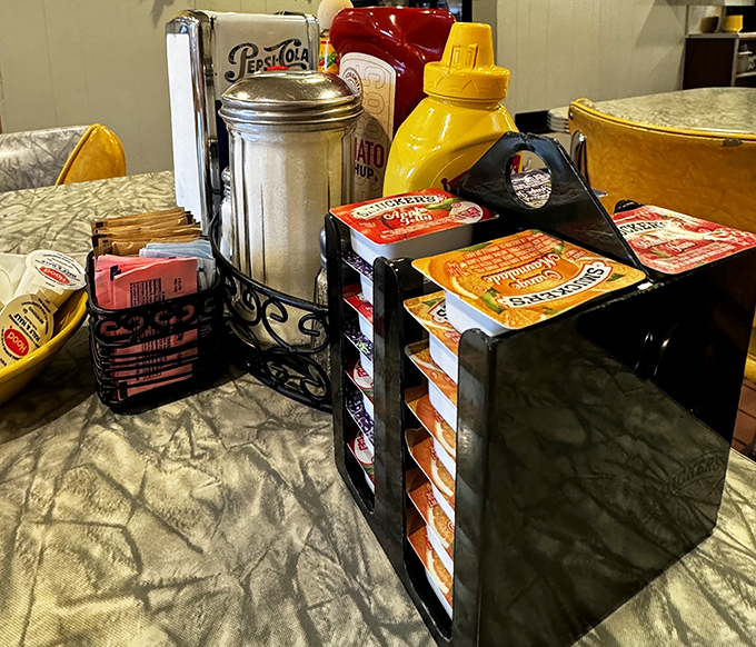 The table essentials: sugar packets organized with military precision, classic diner syrup dispensers, and condiments standing ready for duty like breakfast soldiers.