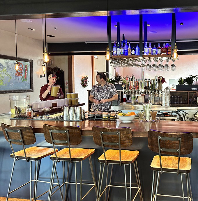 The bar seating offers front-row tickets to the cocktail show, with warm wood tones and vintage-inspired chairs that invite lingering.