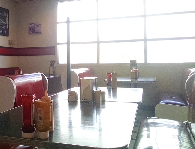 Sunlight streams through windows illuminating condiment bottles standing like sentinels guarding your dining experience.