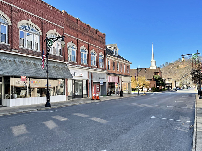 Sunlight plays across storefronts that have weathered economic storms with dignity. The church steeple reminds us what truly anchors a community.