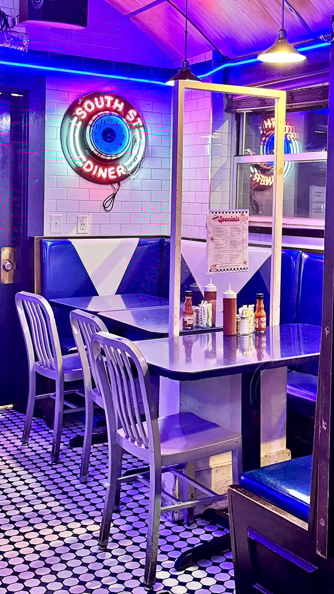 Retro booth seating bathed in blue neon light, where the clock-shaped sign reminds you that time is irrelevant when comfort food awaits.