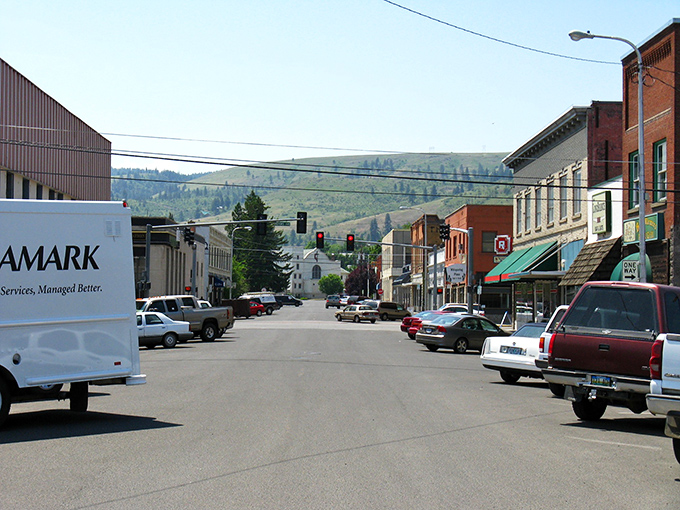 La Grande's charming downtown street showcases classic small-town America with historic buildings framed by beautiful rolling green hills.