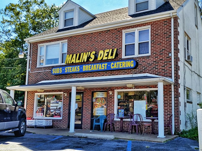 Sunlight catches Malin's yellow sign against the classic brick building, highlighting this beloved neighborhood sandwich institution.