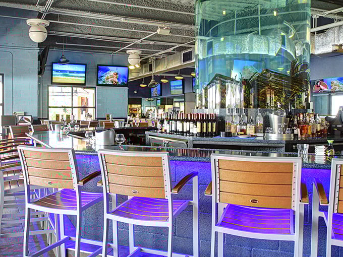 The bar area glows with possibility and premium spirits. That massive aquarium centerpiece reminds you exactly where your dinner came from.