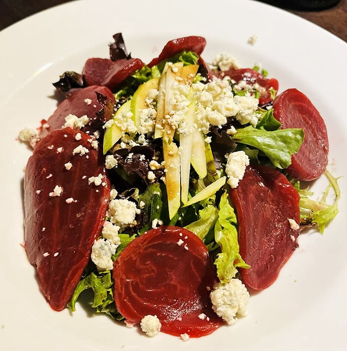 A salad that's having an identity crisis as a work of art—beets and greens playing dress-up with cheese in a delicious masquerade.