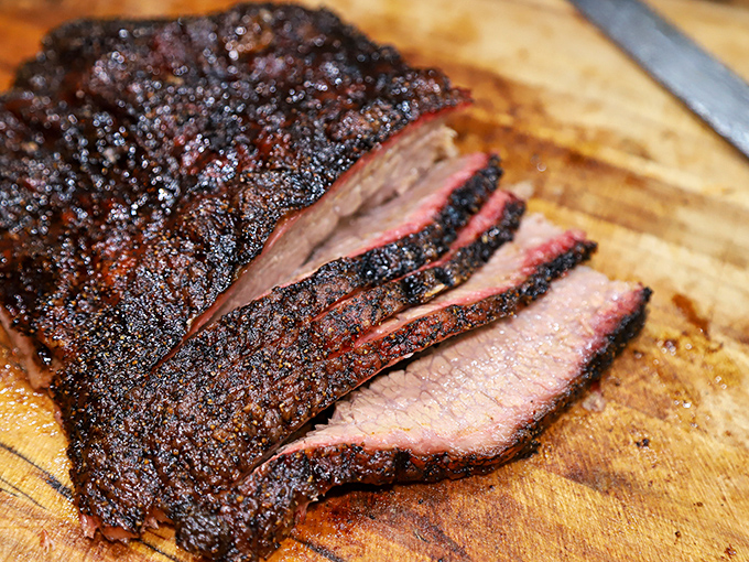 Brisket sliced against the grain reveals the holy trinity of BBQ perfection: smoke ring, rendered fat, and bark that should be illegal in seven states.