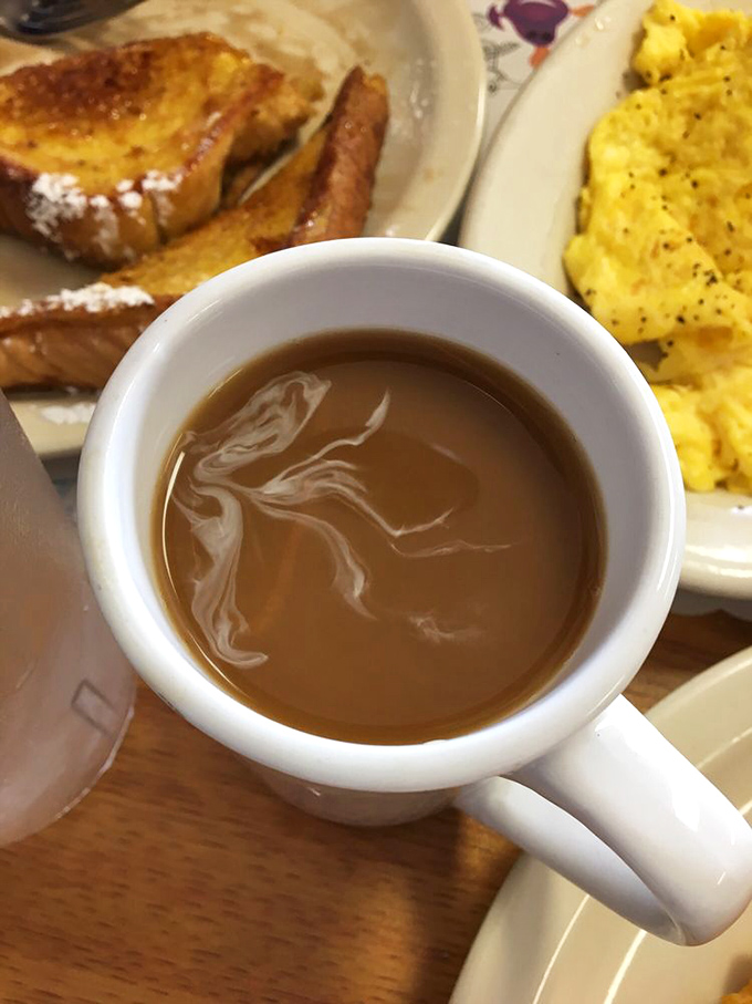 Coffee served in a mug substantial enough to warm your hands. In the background, French toast and eggs wait patiently for their moment of glory.