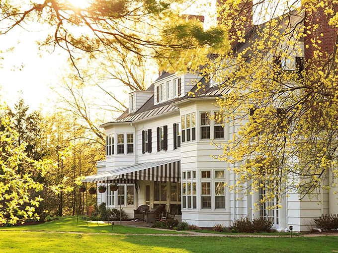 The Four Chimneys Inn basks in golden hour light that photographers chase for a lifetime. Vermont elegance wrapped in white clapboard and sunshine.