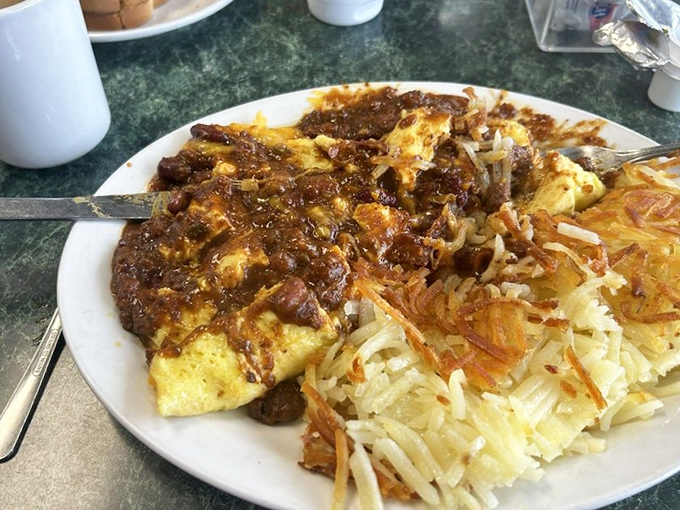 This hearty plate doesn't just feed you—it fortifies you. Savory chili-smothered omelet with a side of hash browns crispy enough to make you weep.
