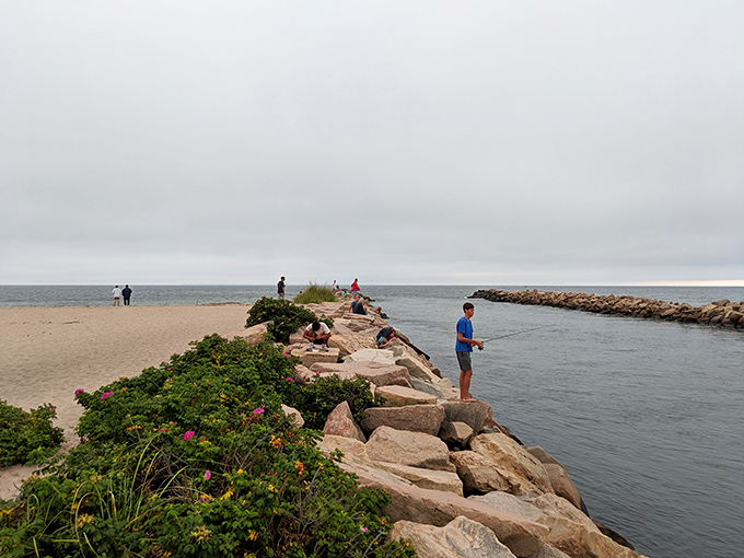 Patience cast in stone. Fishermen line the breachway's rocky edge, their silhouettes becoming part of the landscape as they wait for stripers to make their move.
