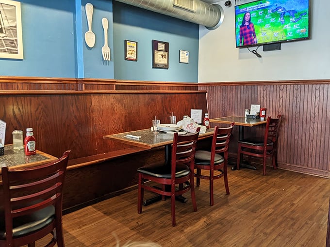 Blue walls adorned with oversized utensils create a playful backdrop for serious eating. This corner booth has witnessed countless coffee refills and satisfied sighs.