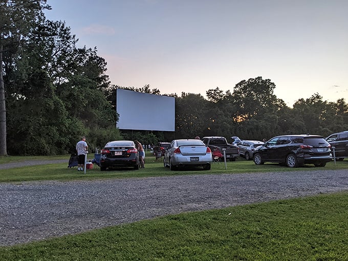 Twilight's golden hour casts a magical glow as moviegoers settle in, positioning their vehicles for the perfect view of cinematic adventures ahead.