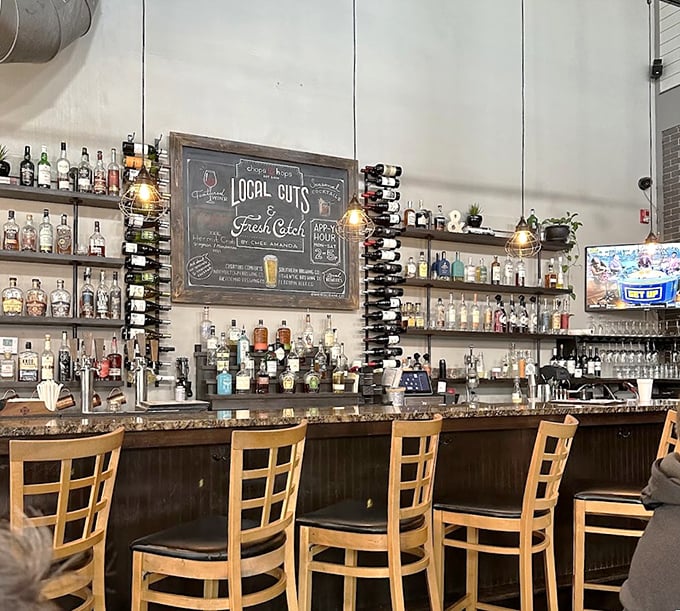 The bar area showcases an impressive selection of spirits beneath warm pendant lighting, where "Local Cuts" and "Fresh Catch" tempt from the chalkboard menu.