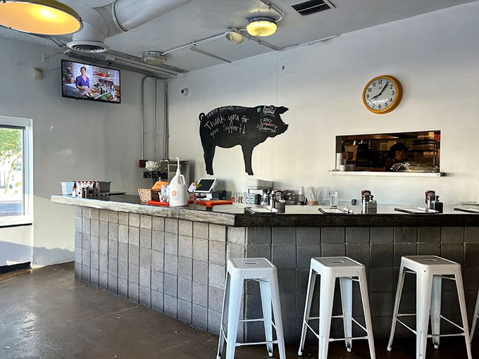 Behind the counter, the pig silhouette watches over a space where stainless steel meets warm wood and every seat offers a view of breakfast magic.