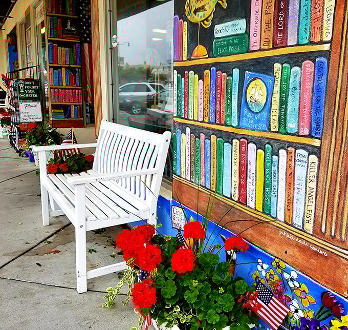A cheerful white bench invites passersby to pause and admire the hand-painted bookshelf mural &ndash; a sidewalk preview of the literary magic inside.