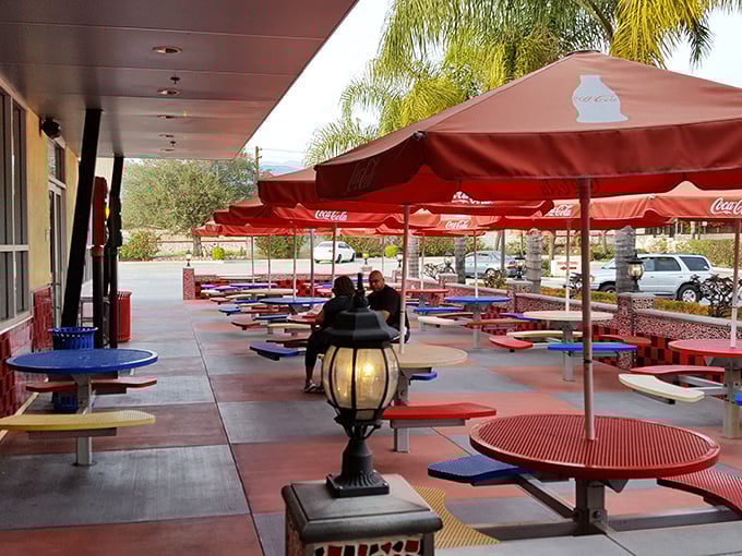 The outdoor dining area offers red umbrella-shaded tables where you can enjoy your meal while soaking up that famous California sunshine.