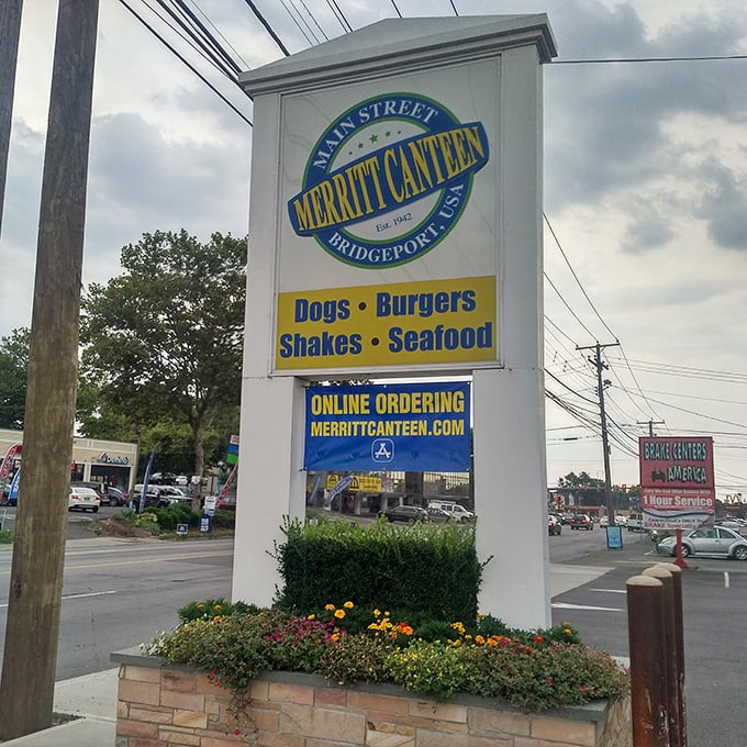 The roadside sign stands as a landmark for hungry travelers, promising the holy quartet of American comfort: Dogs, Burgers, Shakes, and Seafood.