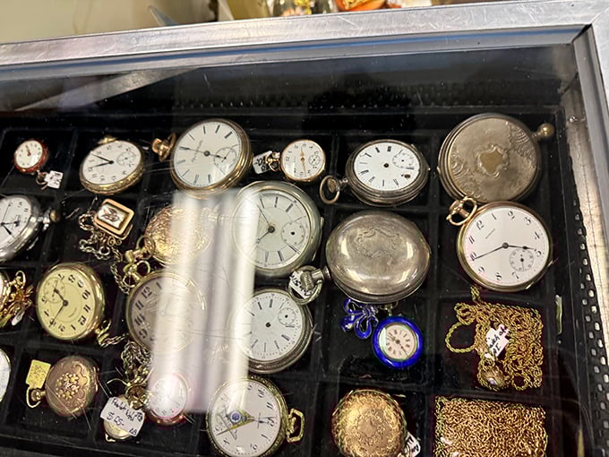 Pocket watches that once kept railroad conductors punctual now rest behind glass, their chains coiled like sleeping snakes of gold and silver.