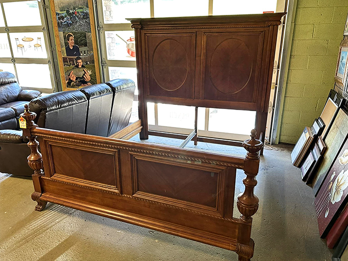 A stately wooden bed frame stands regally alone &ndash; someone's future heirloom waiting for its next chapter.