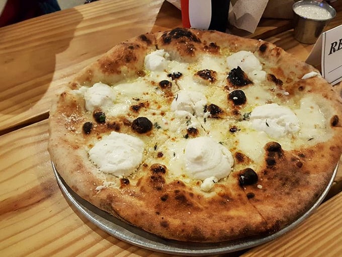 The white pizza that proves sometimes the absence of red sauce creates a canvas for flavors that whisper rather than shout.