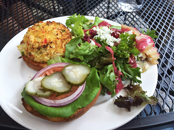 This crab cake sandwich towers proudly over fresh greens&mdash;minimal filler, maximum flavor, pure Chesapeake Bay happiness on a bun.
