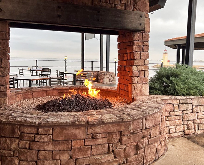 The stone fire pit adds primal warmth to evening dining, hypnotic flames dancing against the lakeside backdrop.