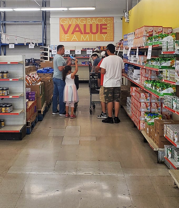 The "GIVING BACK VALUE FAMILY" sign says it all. Real people finding real bargains in aisles that feel like community, not commerce.