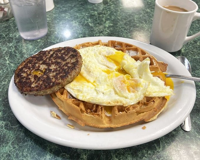 Breakfast architecture at its finest—a golden waffle foundation supporting eggs and sausage in perfect harmony. The breakfast of champions.