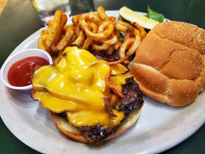 A cheeseburger wearing its melted yellow badge of honor proudly, with curly fries standing at attention nearby.