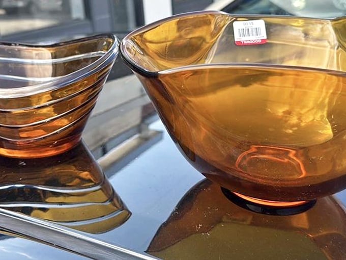 Amber glass bowls catching light like liquid honey. Vintage serving pieces that would cost a fortune in trendy boutiques wait here for discerning eyes.