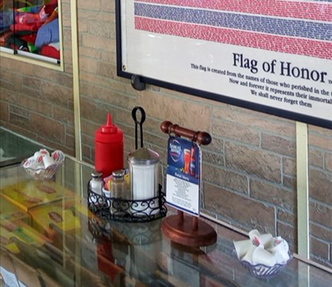 Ketchup and condiments wait at the counter beside a Flag of Honor, because patriotism and breakfast belong together in small-town America.