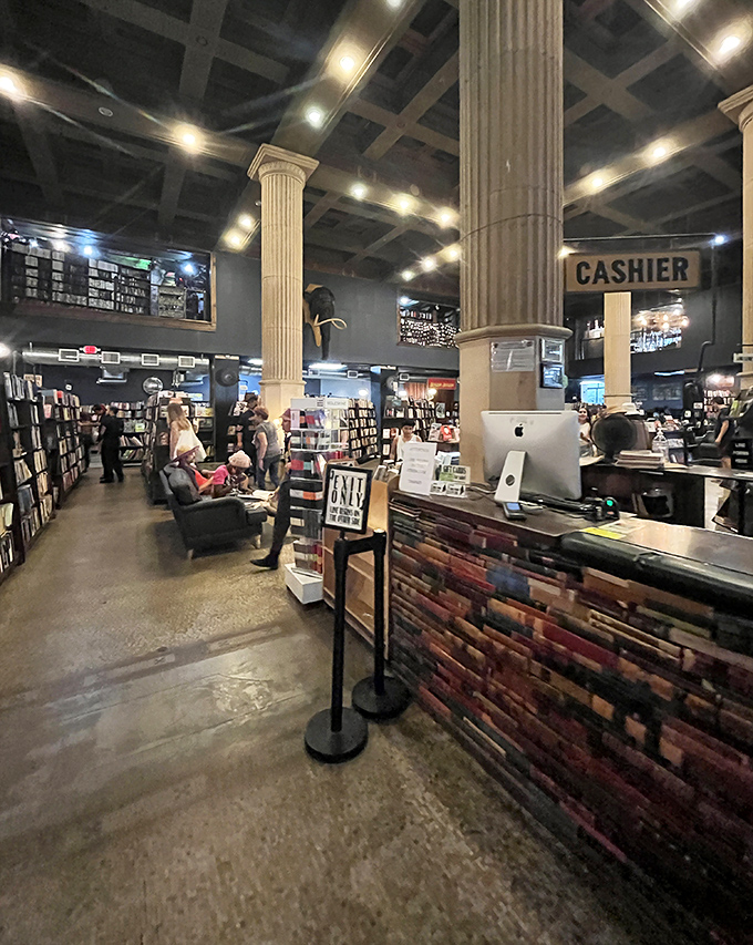 The checkout counter where dreams are purchased by the pound. That book-spine counter front is pure literary genius.