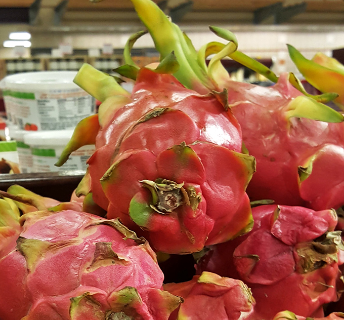 Exotic dragon fruit sits proudly among the produce, looking like something that arrived from another planet rather than the grocery supply chain.