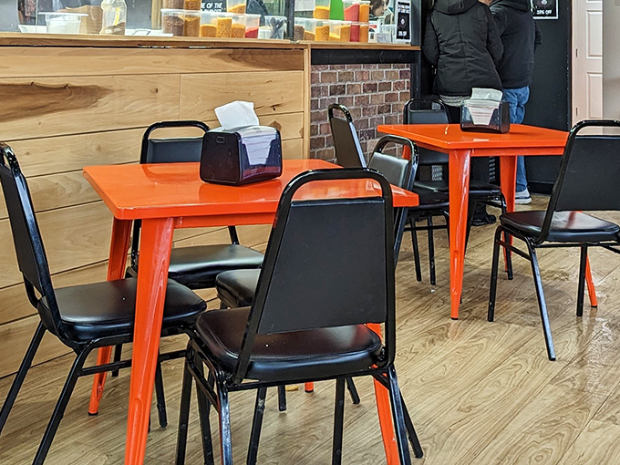 Bright orange tables pop against black chairs in a space that's both modern and welcoming. Comfort food deserves comfortable surroundings.
