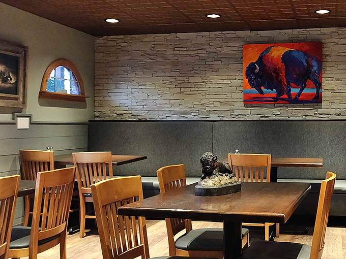 Warm wood tones and stone walls create the perfect backdrop for breakfast conversations. The vibrant buffalo artwork watches over diners like a colorful guardian.