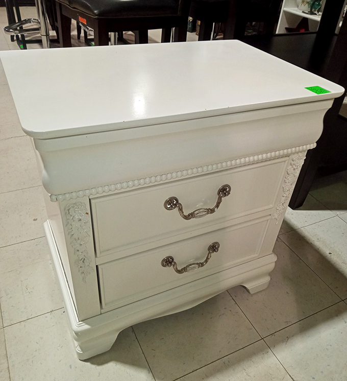 This pristine white nightstand whispers tales of bedroom elegance from another era. Those silver handles have probably opened drawers for generations of midnight snackers.