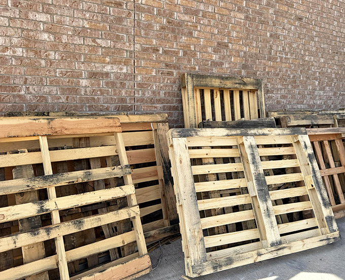 Free pallets lean against the brick wall, perfect for crafty DIYers with Pinterest boards full of ideas.
