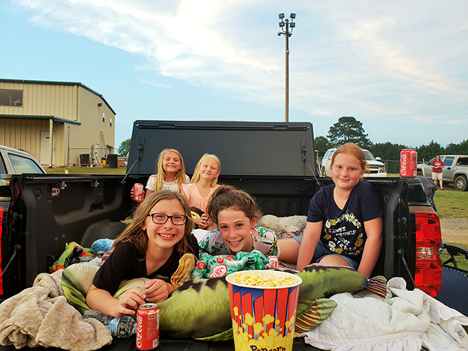 Movie night elevated: kids, Coca-Cola, and a giant bucket of popcorn in a truck bed theater. Childhood memories in the making.