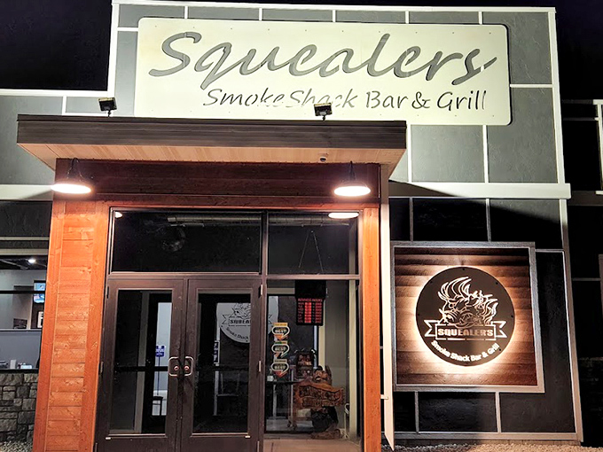 As night falls, the illuminated Squealer's sign becomes a beacon of hope for the hungry, promising smoky salvation within its walls.