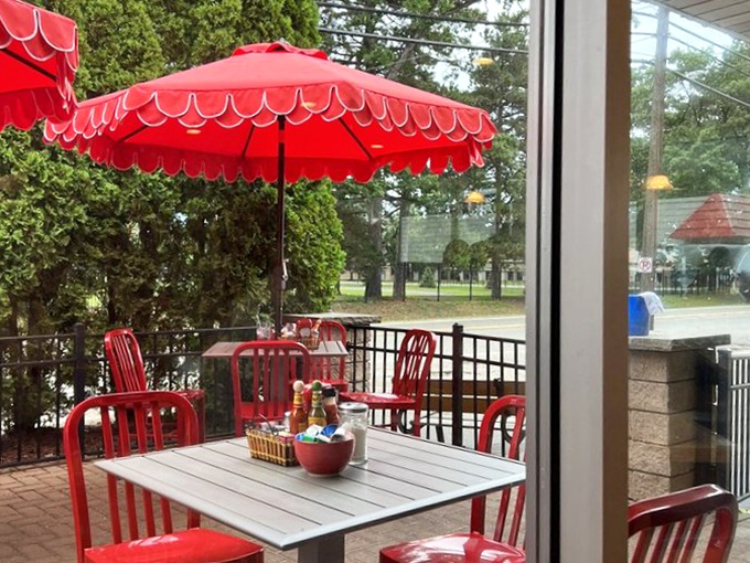 The patio's crimson ensemble pops against Michigan greenery &ndash; a breakfast oasis waiting just beyond the glass.