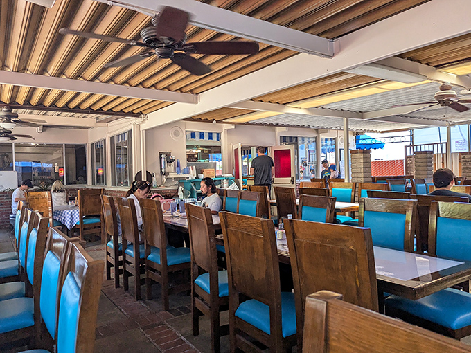 The dining room where breakfast dreams come true—wooden chairs, blue cushions, and ceiling fans that have witnessed decades of "I'll just have one more bite."