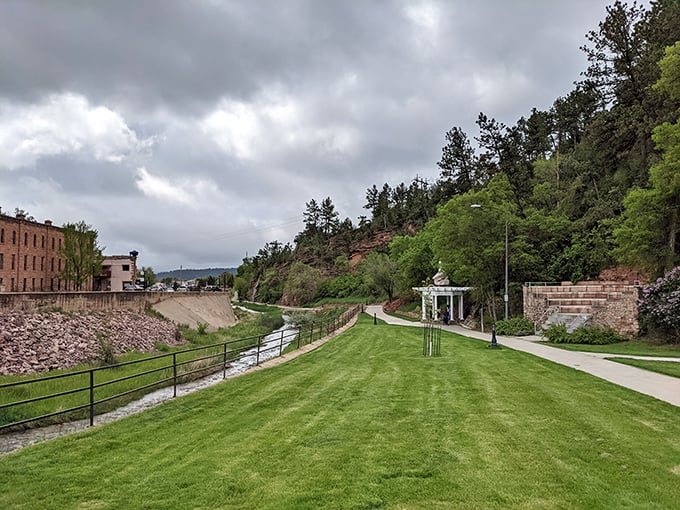 The riverside walk offers manicured green space alongside Fall River's gentle flow. Nature and civilization finding their perfect balance.