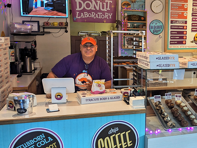 Behind the counter, friendly staff serve up smiles alongside boxes proudly declaring their contents "Syracuse Born & Glazed."