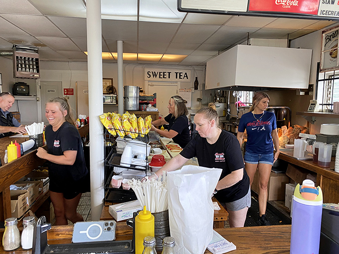 The kitchen crew moving with practiced efficiency, churning out hot dogs like a well-oiled machine that actually smiles.
