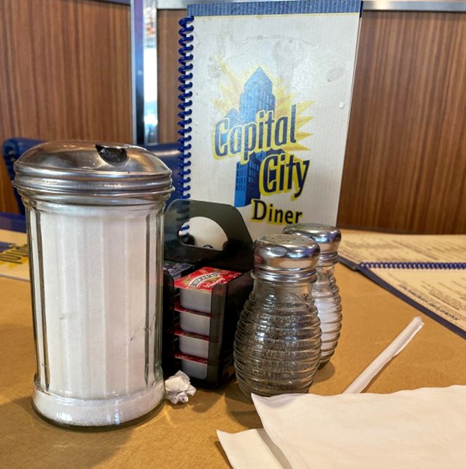 The classic diner table setup&mdash;sugar, salt, pepper, and napkins standing at attention, ready to support whatever culinary adventure you're about to embark on.