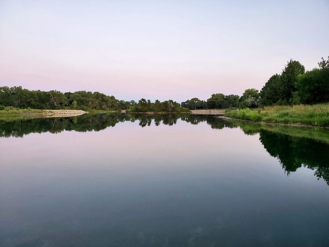 Cottonmill Lake's mirror-like surface perfectly captures twilight's gentle palette, offering a moment of reflection at the end of a perfect Kearney day.