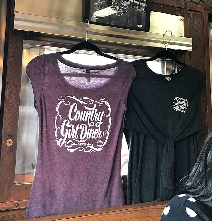 Wearable souvenirs that let you carry a piece of diner magic home &ndash; purple and black tees hanging like backstage passes.