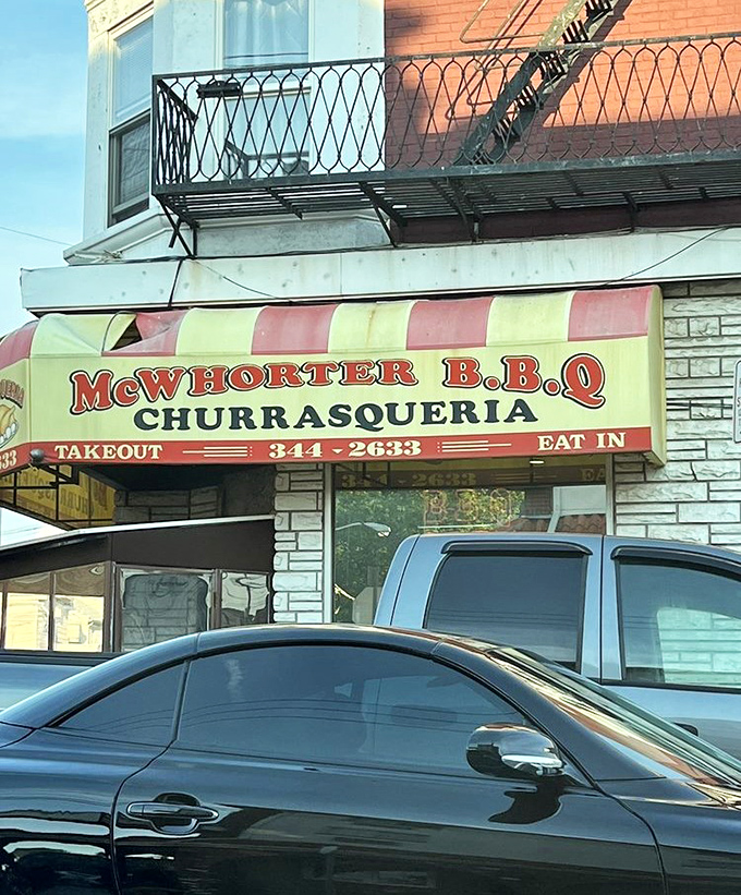 The iconic red and yellow awning serves as a beacon for barbecue pilgrims. Cars parked outside belong to those in-the-know about Newark's flavor headquarters.