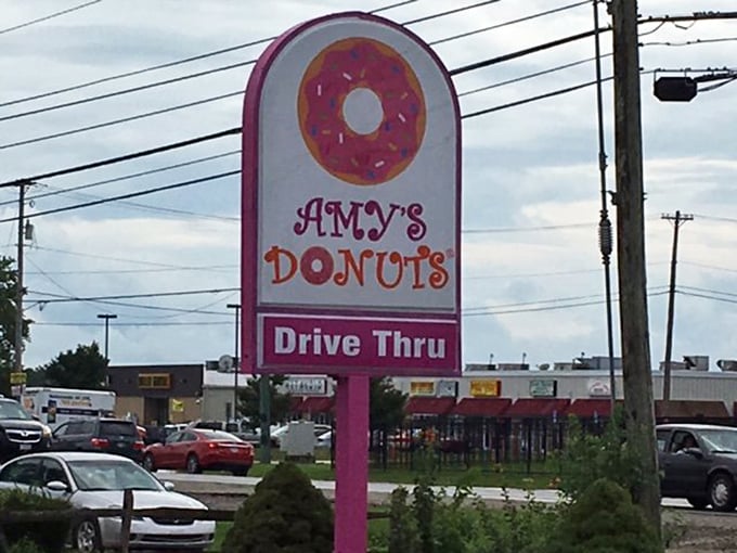 The roadside sign serves as a pink-and-white lighthouse, guiding hungry travelers safely to shore. Follow it to donut salvation.