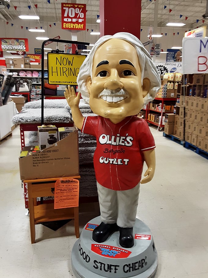 The smiling mascot greets shoppers like an old friend, a plastic prophet of savings in a world of retail markups.